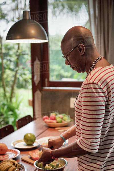 Mature man at kitchen table preparing fruit in bowl - Royalty-free ...
