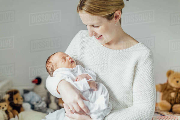 Mother holding newborn baby girl, smiling - Stock Photo - Dissolve