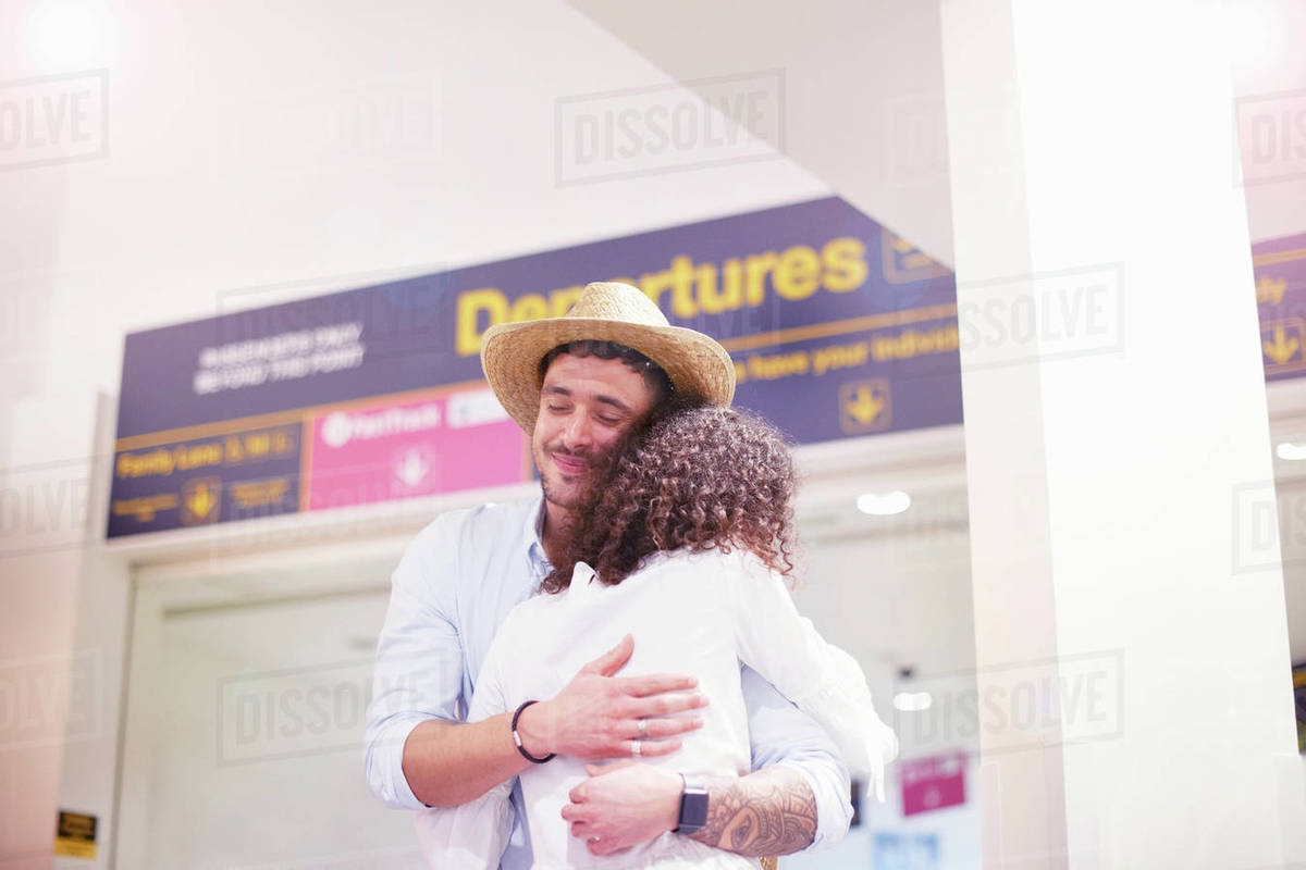 Man and woman hugging at departure lounge of airport - Royalty-free ...
