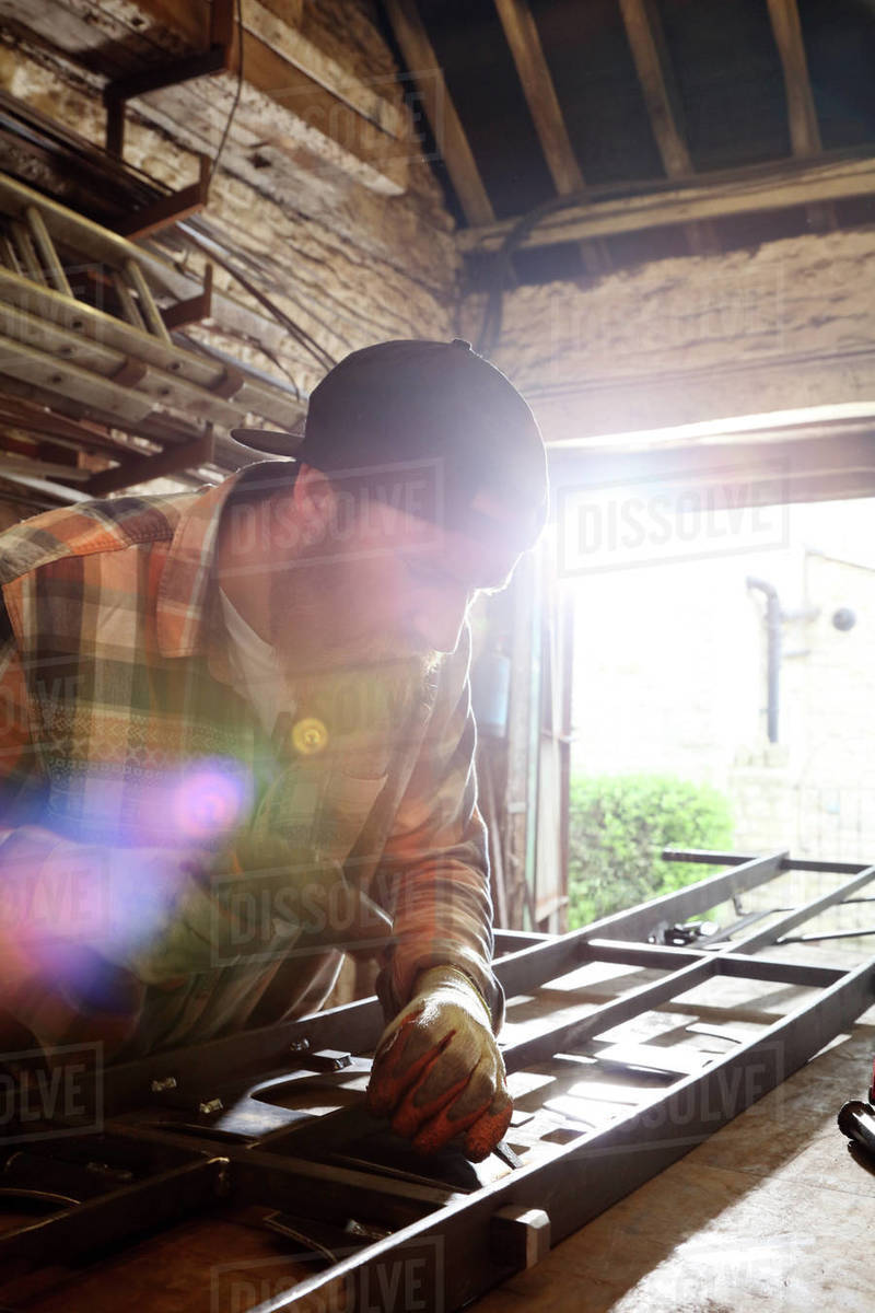 Blacksmith hammering metal on workbench in blacksmiths shop - Royalty ...