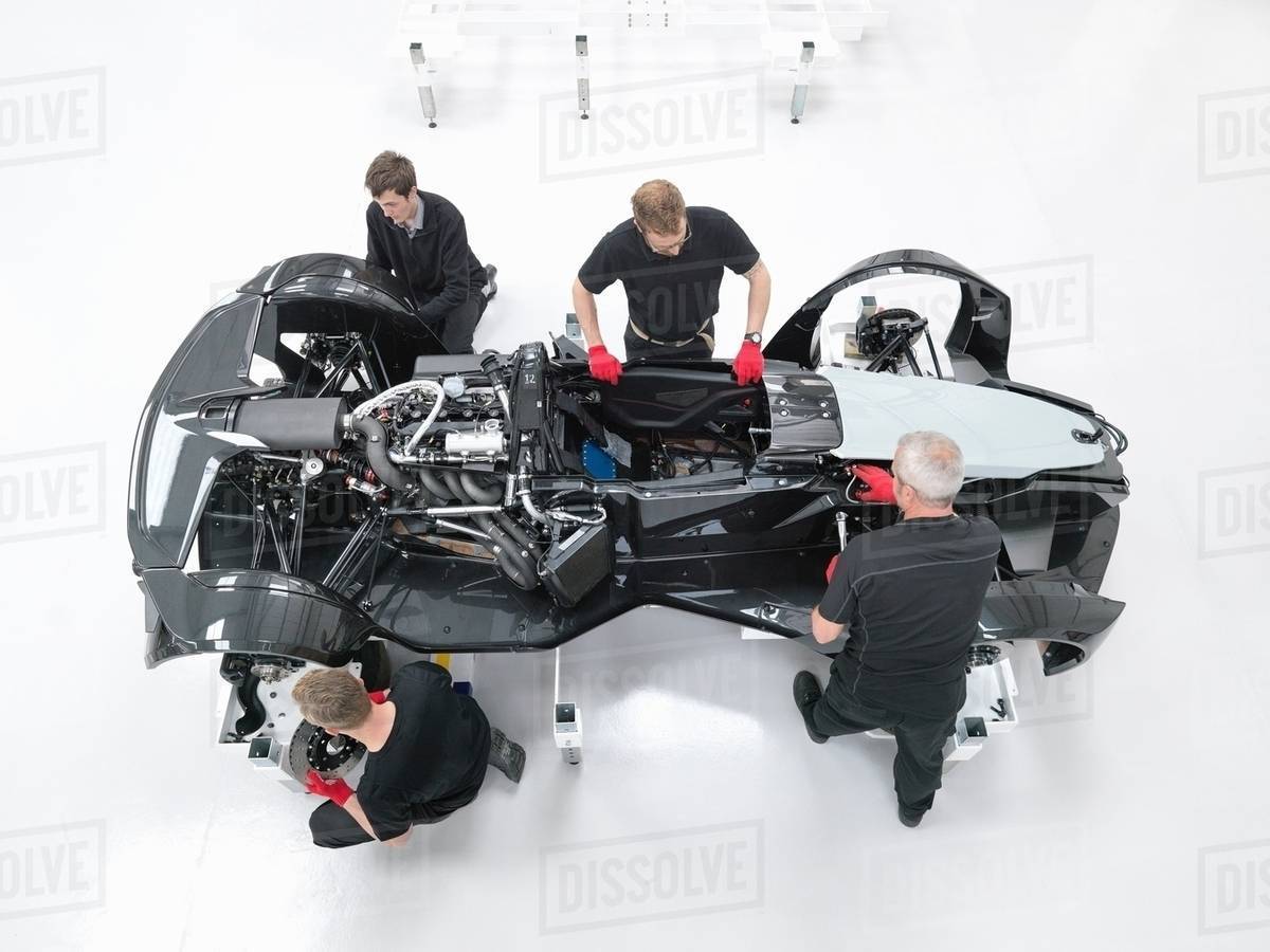 Overhead view of engineers assembling supercar in sports car factory ...