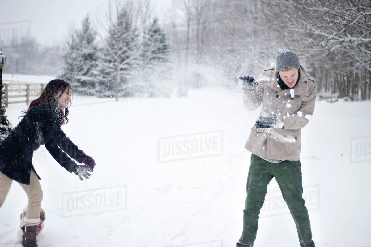 Young couple having snowball fight in snow covered forest, Ontario ...