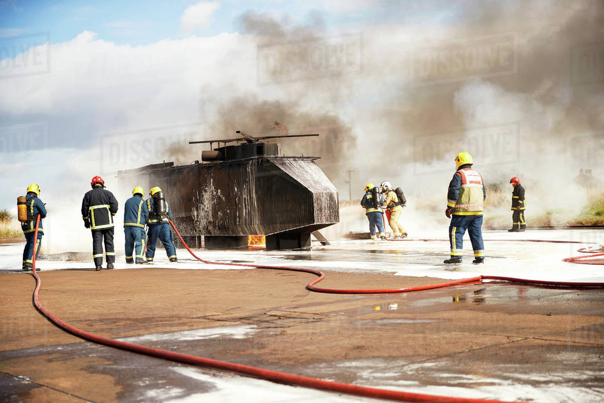 Firemen training, team of firemen spraying firefighting foam at mock ...