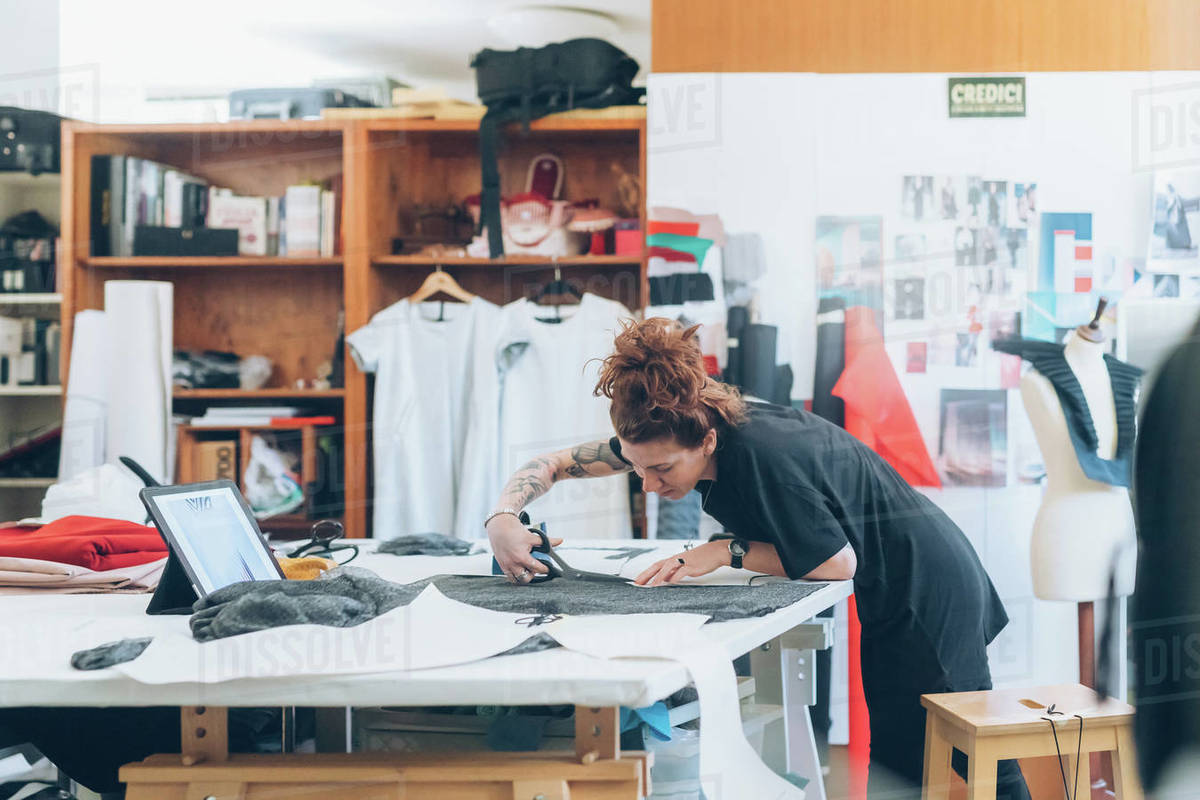 Fashion designer cutting fabric from dressmaker's pattern - Royalty ...