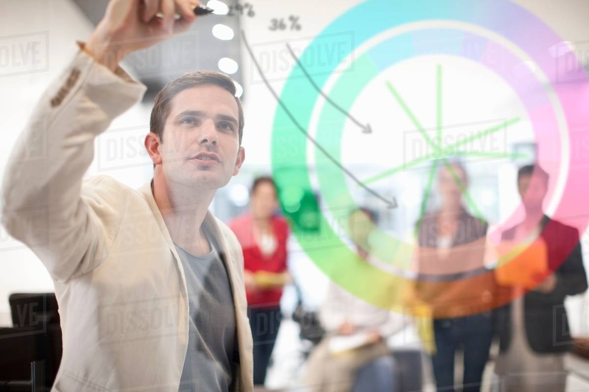 Man writing on glass screen, colleagues watching - Stock Photo - Dissolve