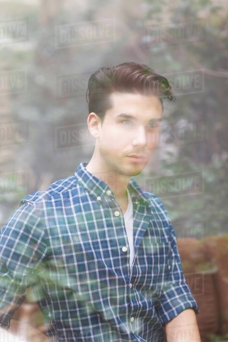 Portrait of young man behind window - Stock Photo - Dissolve