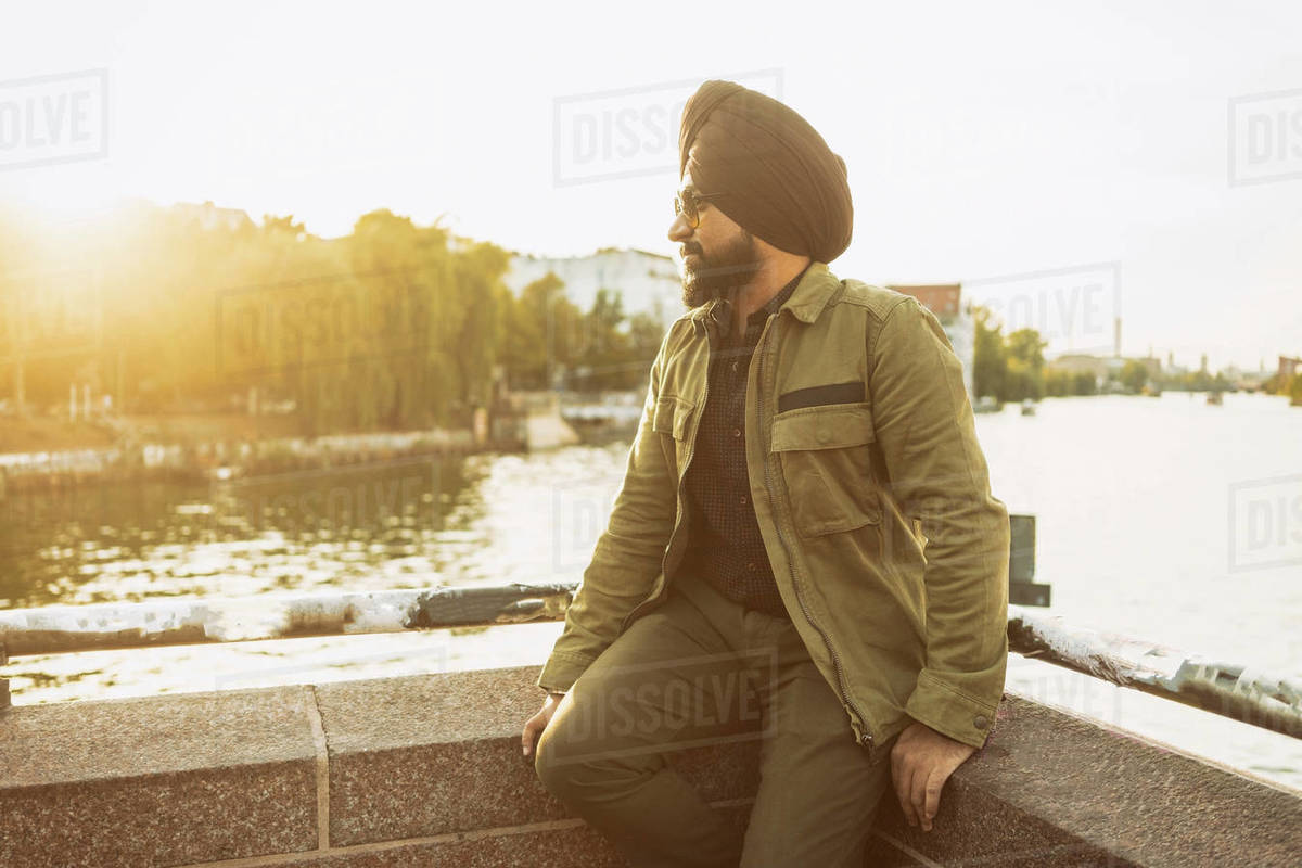 Indian man exploring city, river in background, Berlin, Germany ...