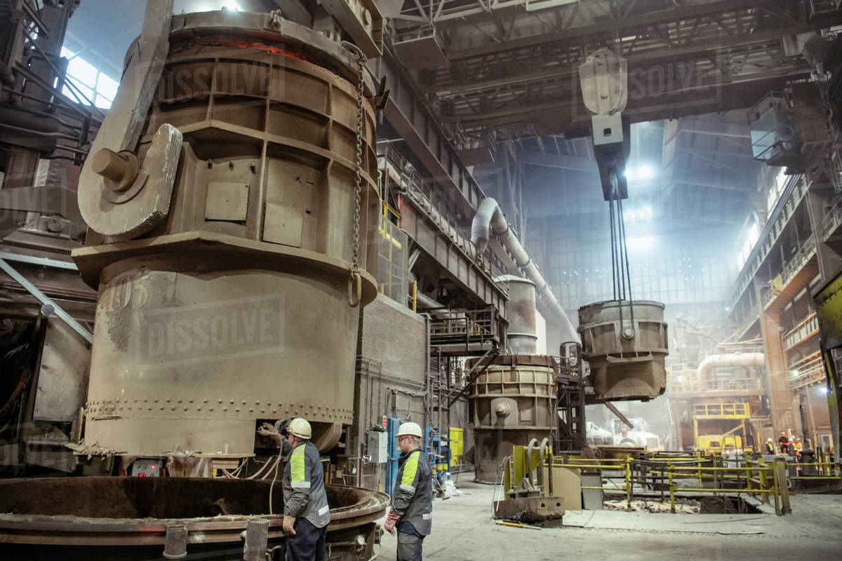 Workers preparing molten steel ladle in steelworks - Stock Photo - Dissolve