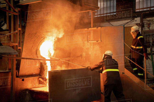 Workers pouring liquid titanium alloy from furnace in titanium ...