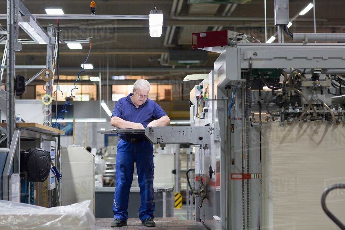 Worker using machine in paper packaging factory - Stock Photo - Dissolve