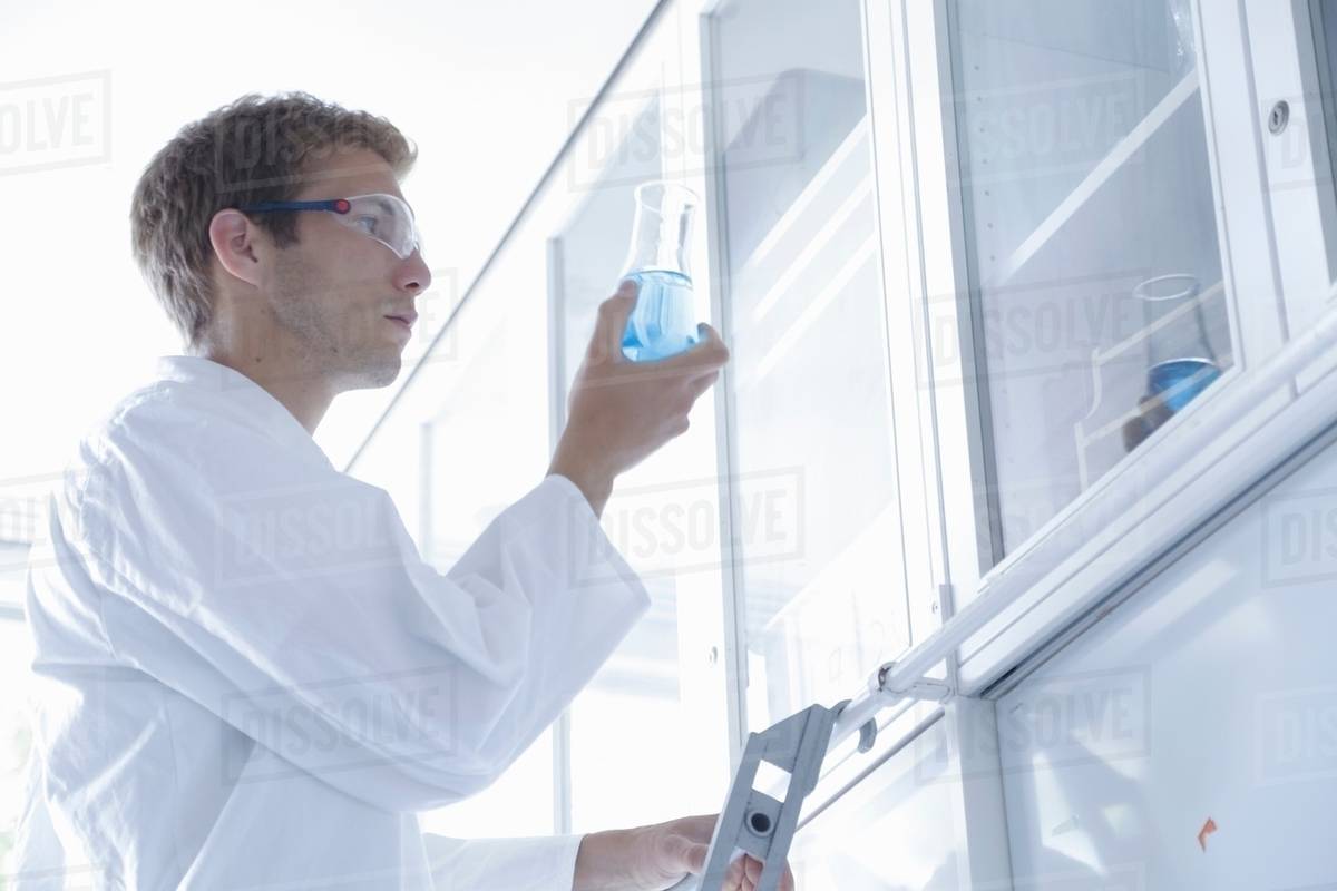 Male scientist scrutinizing erlenmeyer flask in lab - Royalty-free ...