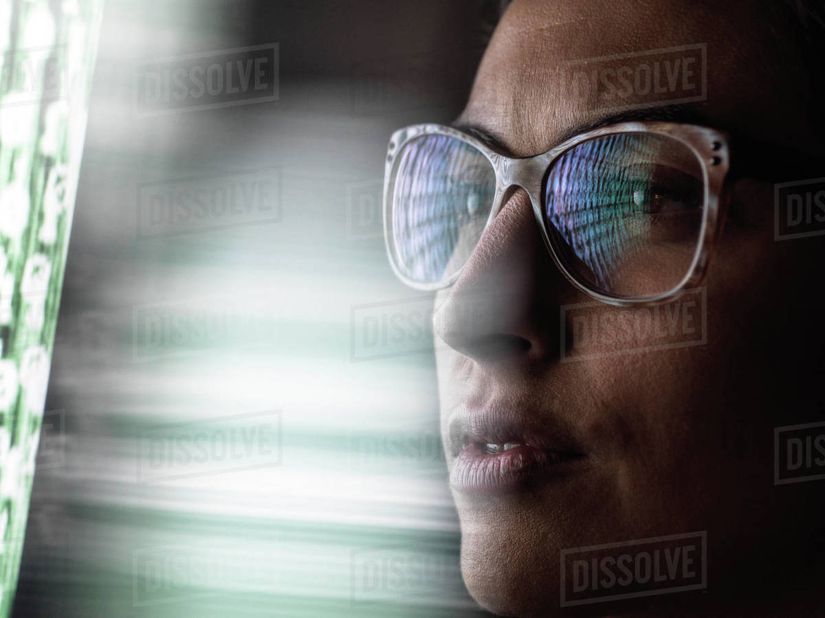 Female data analyst looking at data on screen, reflection in glasses ...