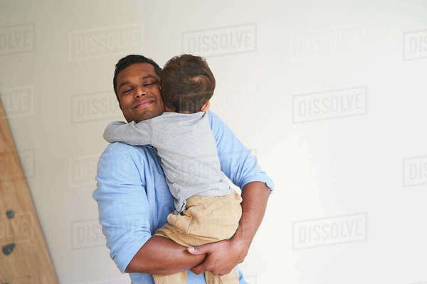 A man smiling, holding and hugging his son. - Stock Photo - Dissolve