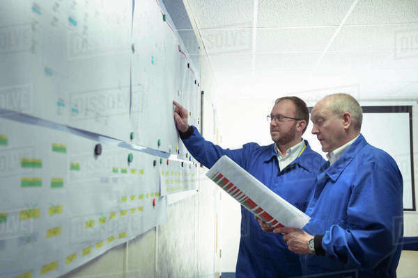 Engineers standing at a notice board in a nuclear power station ...
