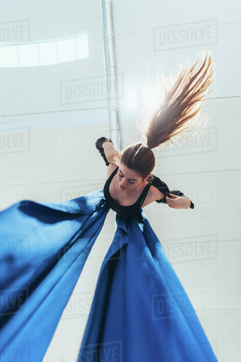 Female acrobat practicing, suspended from blue silk. - Stock Photo ...