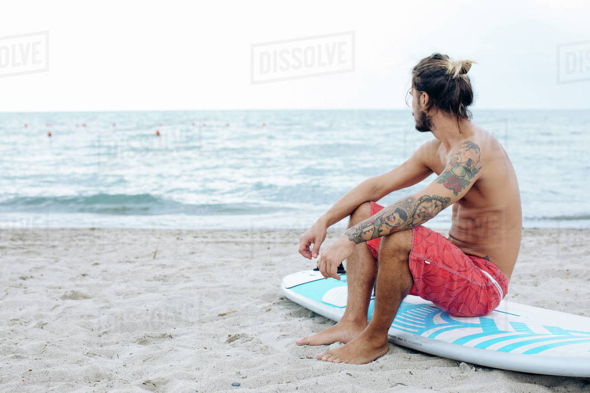 Surfer with surfboard by seaside - Royalty-free Stock Photo | Dissolve