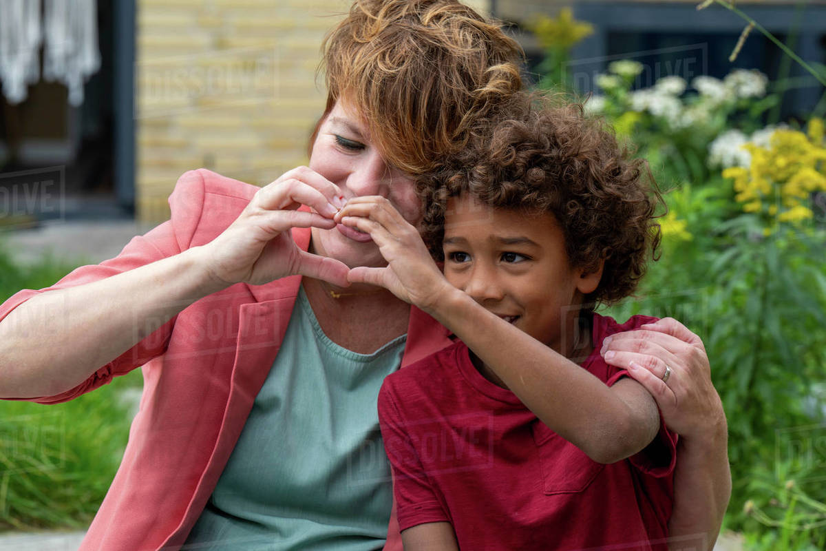 Mixed race mum and son playing in the garden bonding, laughing together ...