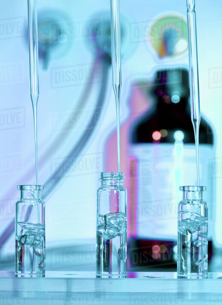 Science in action with pipettes dispensing liquid into test tubes ...