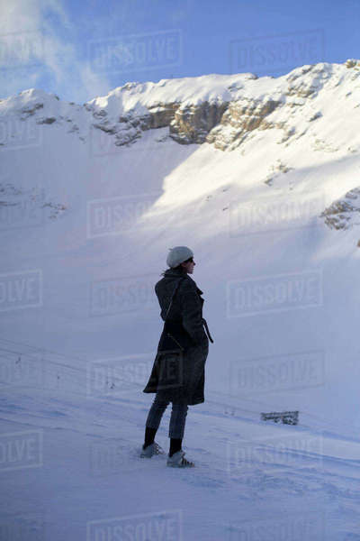 A person stands in a snow-covered landscape gazing at the towering ...