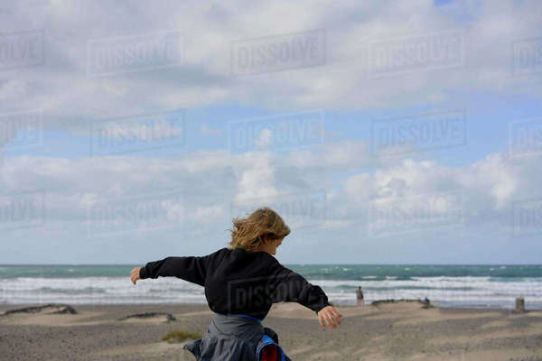 A person stands on a rocky overlook gazing out at a scenic coastal ...