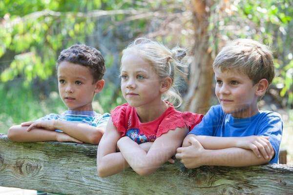 Three children leaning on fence looking away - Royalty-free Stock Photo ...