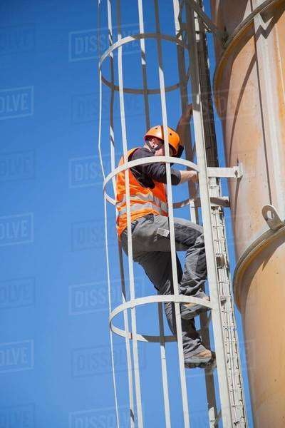 Worker climbing smoke stack ladder - Stock Photo - Dissolve