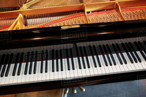 The image features a close-up view of a grand piano's open lid ...