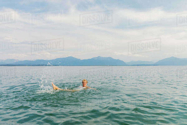 Shirtless man standing on the deck of a sailboat with a clear blue sky ...