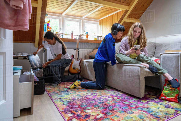 Three children engage in different activities in a cozy living room ...