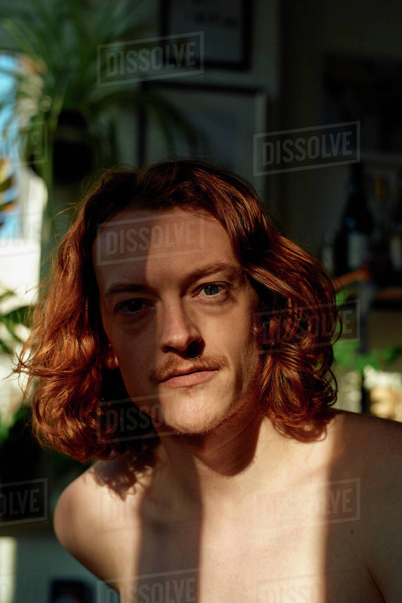 Half-lit portrait of a shirtless man with shoulder-length wavy hair in ...