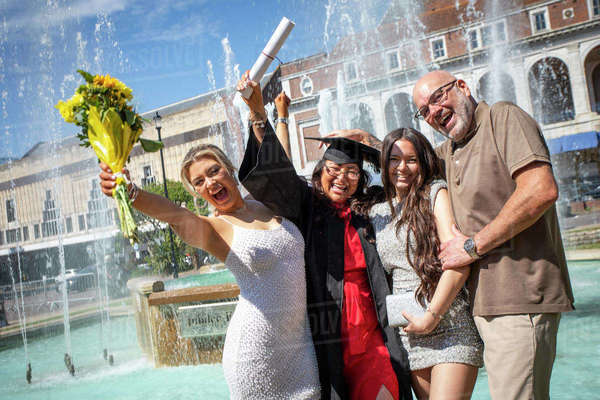 Group of happy people celebrating a graduation with a bouquet and ...
