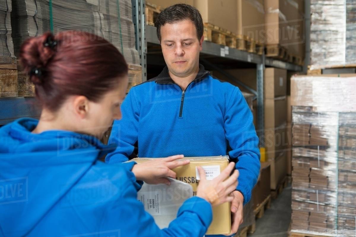 Factory workers labelling parcel - Stock Photo - Dissolve