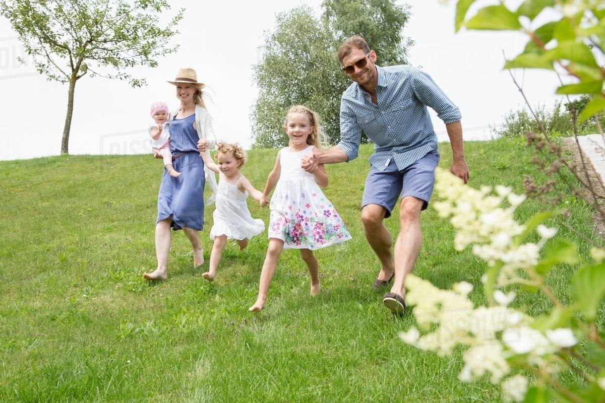 Family running through field - Stock Photo - Dissolve