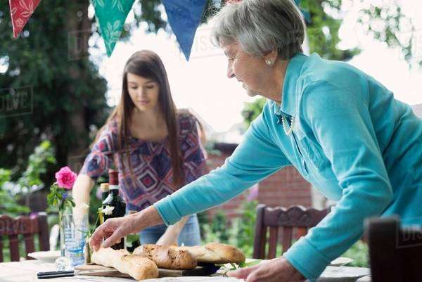 Senior woman setting the table outdoors - Stock Photo - Dissolve