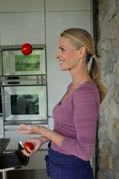 Mature woman juggling tomatoes - Royalty-free Stock Photo | Dissolve