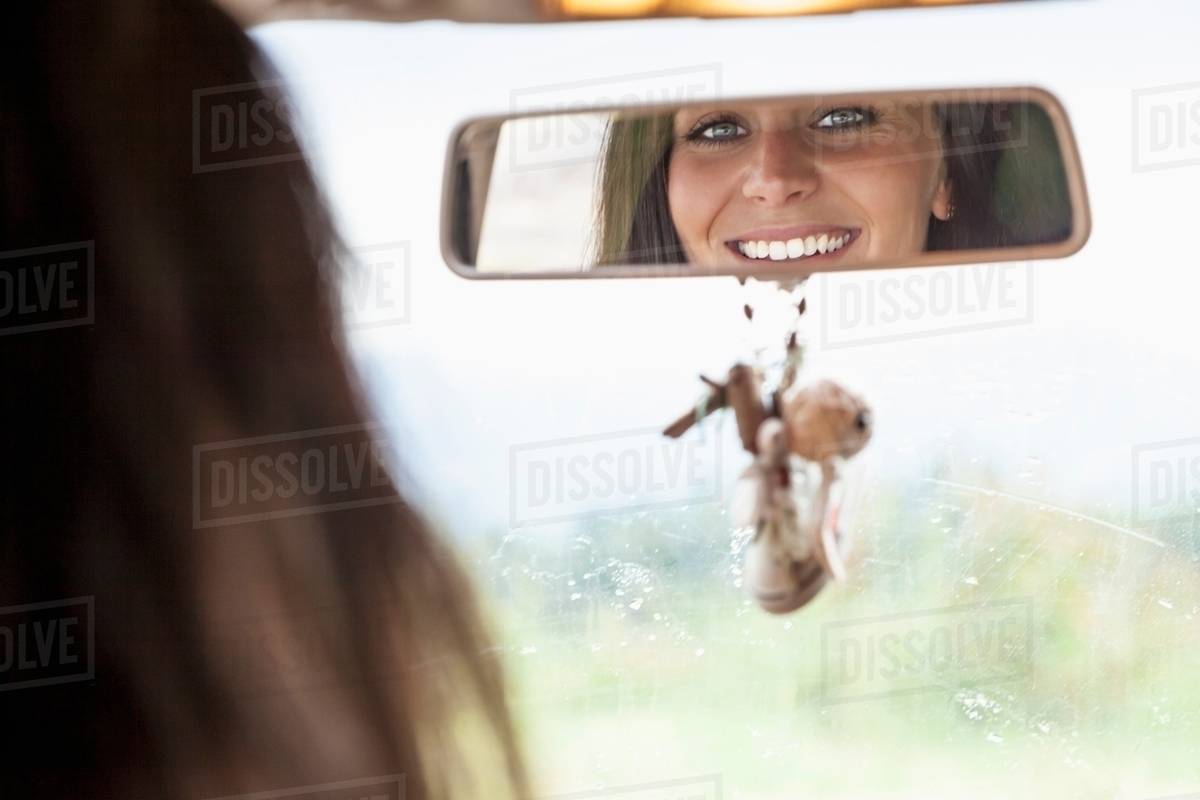 Young woman looking in rear view mirror - Stock Photo - Dissolve