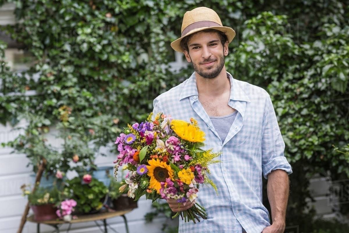 Portrait of young man with bunch of flowers in garden - Stock Photo ...