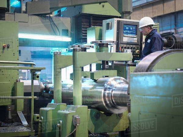 Engineer working at lathe in engineering factory - Stock Photo - Dissolve