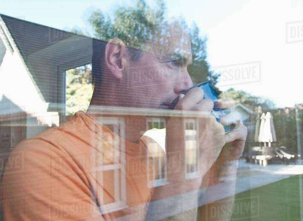 Man having coffee reflected in window - Stock Photo - Dissolve