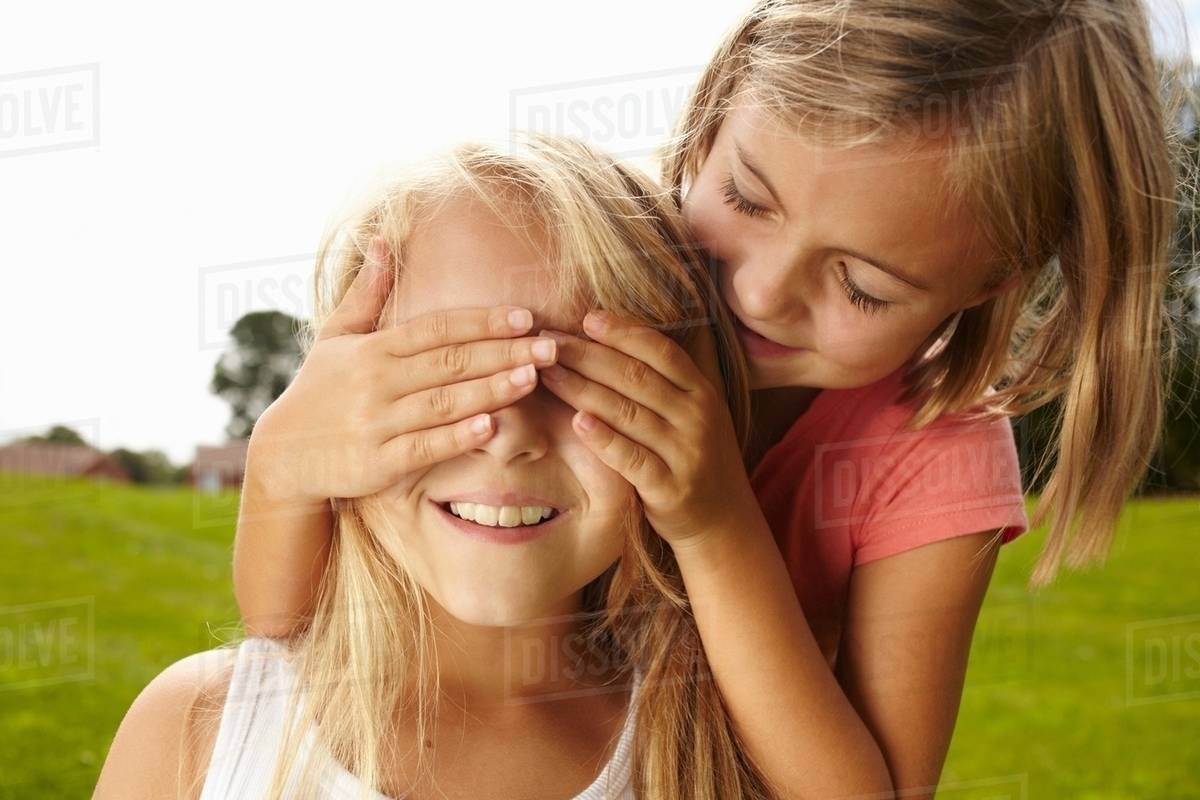 Smiling girl covering friends eyes - Royalty-free Stock Photo | Dissolve