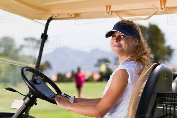 Woman driving golf cart on course - Stock Photo - Dissolve