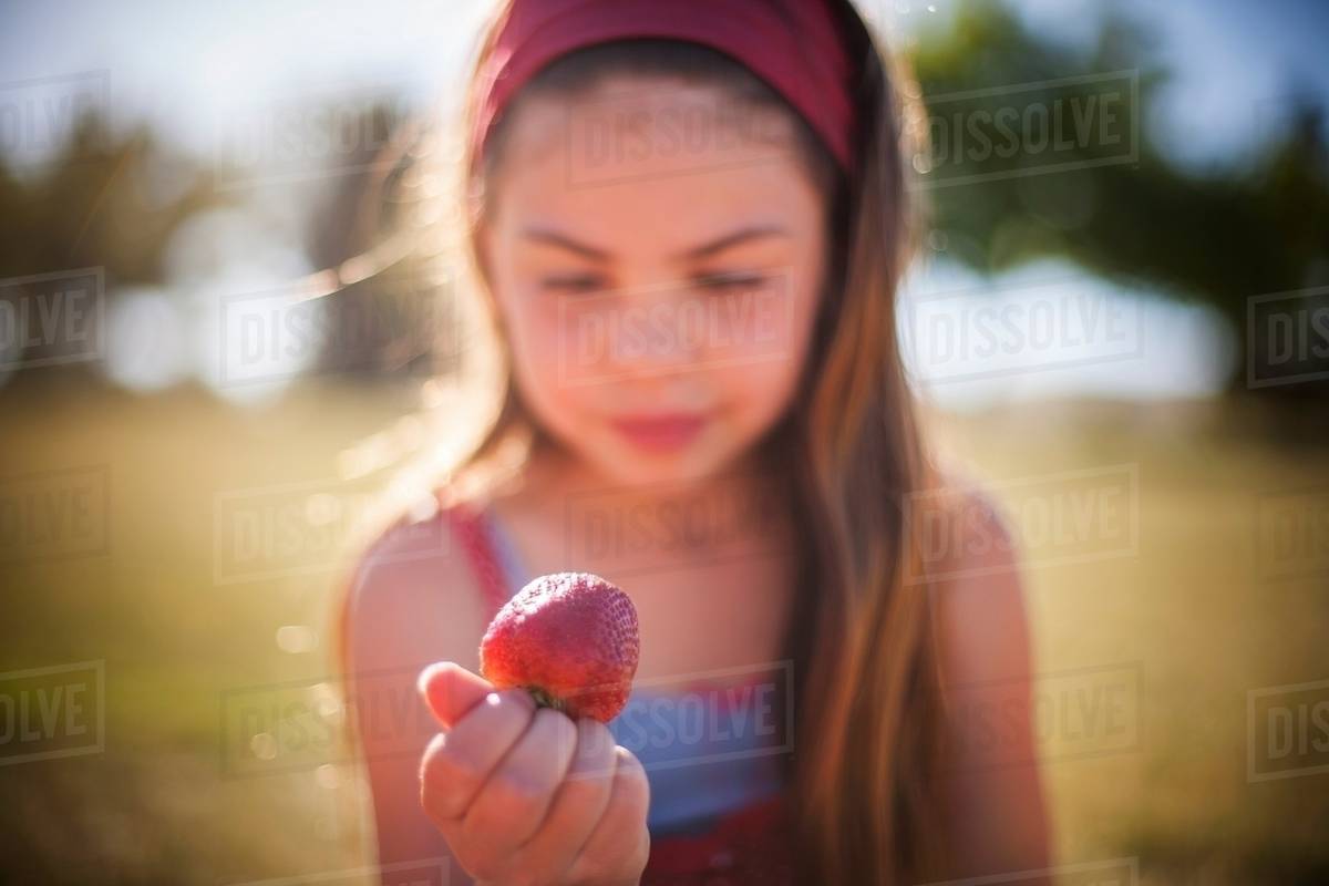 Girl eating strawberry outdoors - Stock Photo - Dissolve