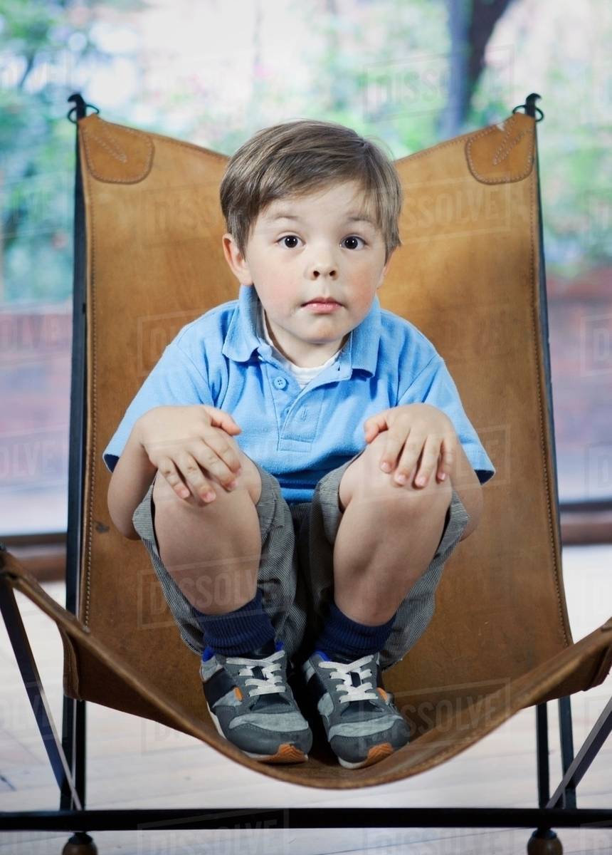Boy crouching in camp chair - Royalty-free Stock Photo | Dissolve