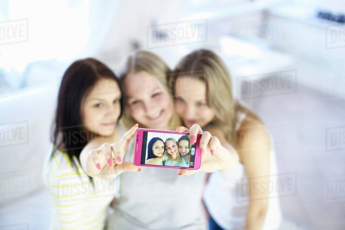Teenage girls taking picture together - Stock Photo - Dissolve