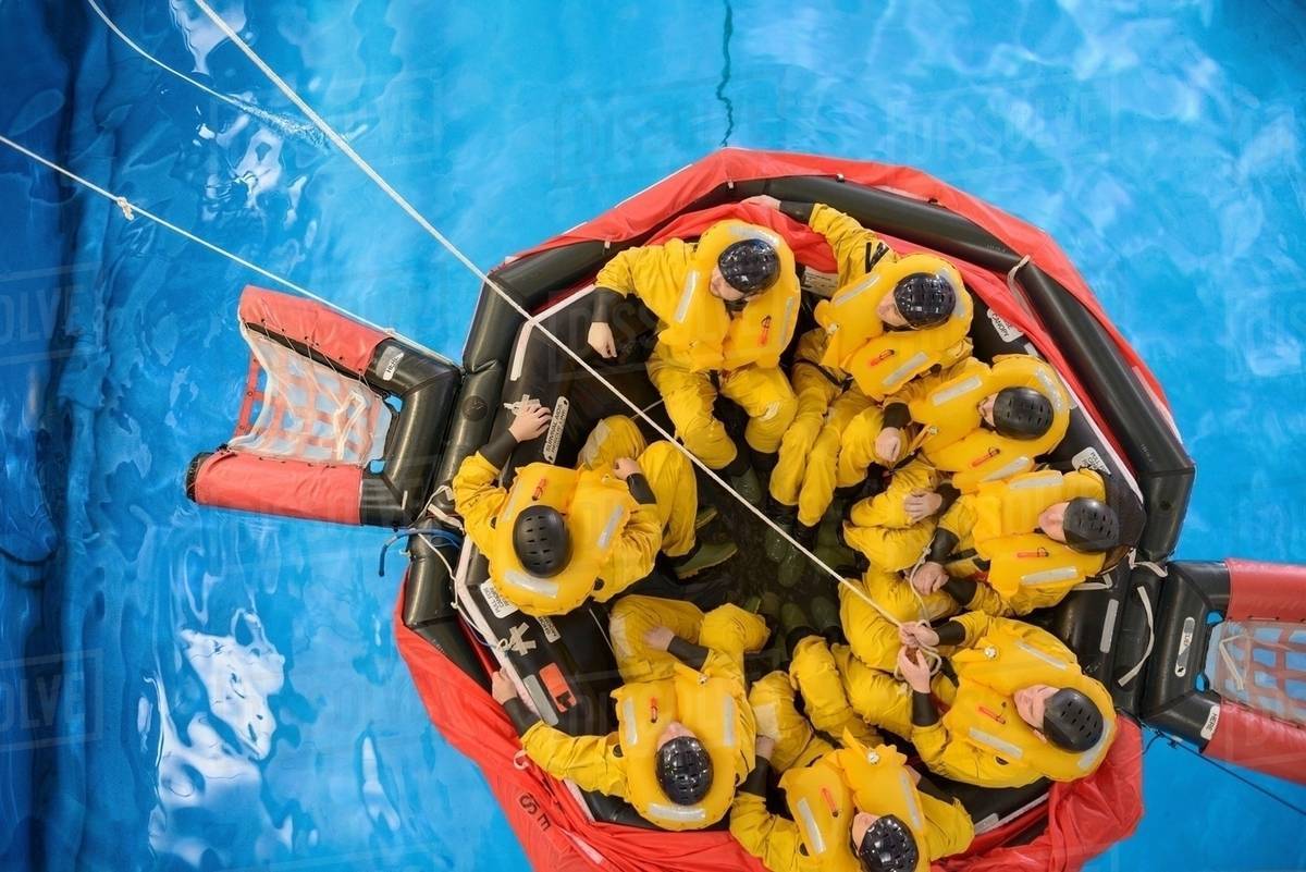 Offshore oil workers in raft being trained in sea ditching survival in ...
