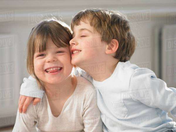 Smiling children hugging indoors - Stock Photo - Dissolve