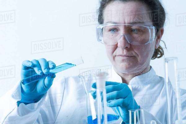 Scientist pouring liquid into beaker - Royalty-free Stock Photo | Dissolve