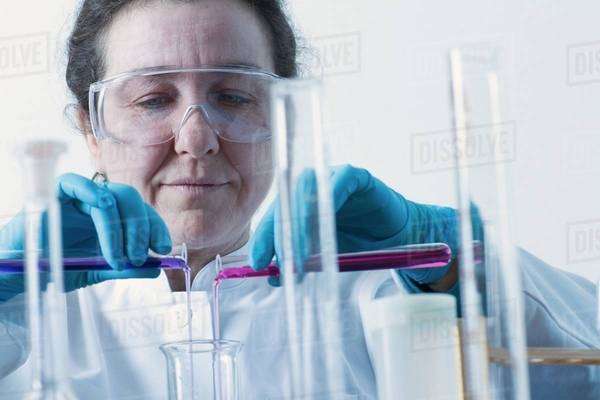 Scientist pouring liquid into beaker - Royalty-free Stock Photo | Dissolve