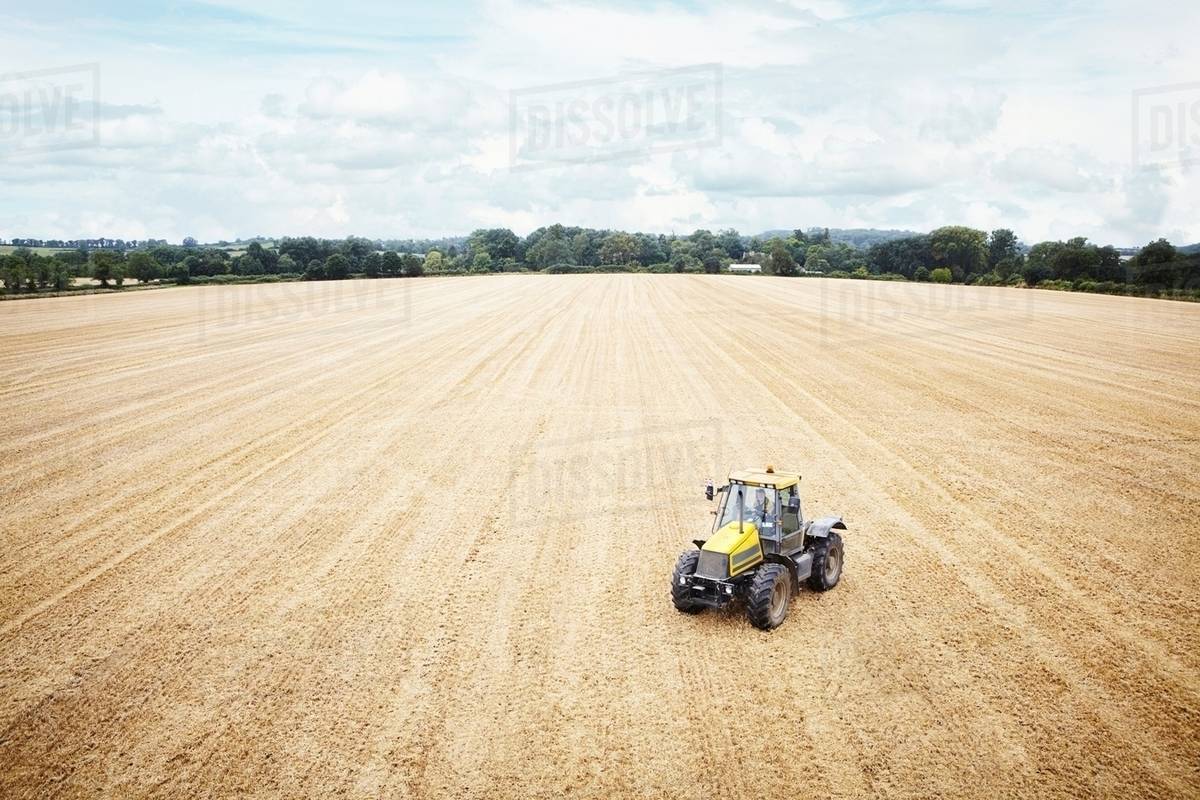 Tractor driving in tilled crop field - Royalty-free Stock Photo | Dissolve