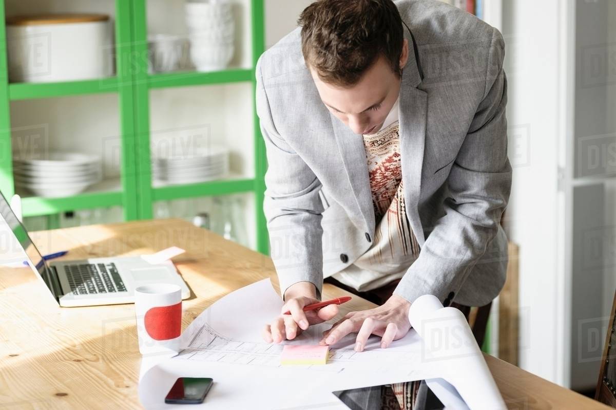 Man bending over work documents - Stock Photo - Dissolve
